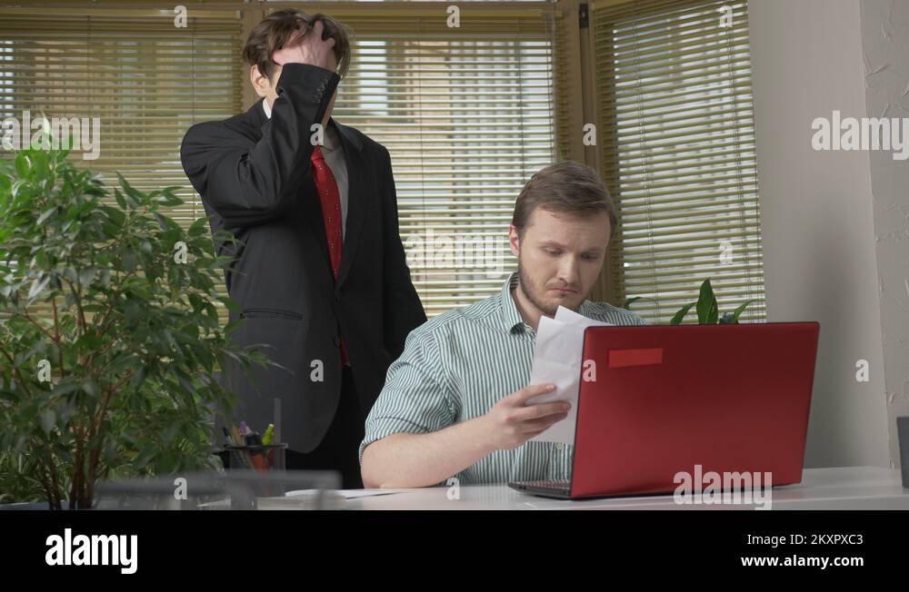 Angry boss checks report a young guy in a suit, employee. Work in the ...