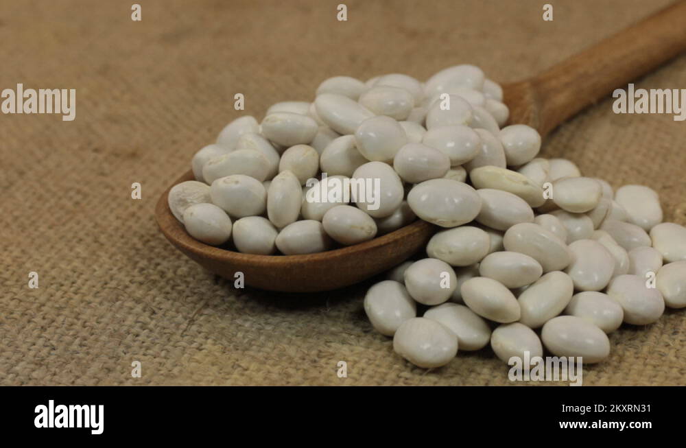 Rotating a spoon, overflowing with haricot beans, lying on burlap Stock ...