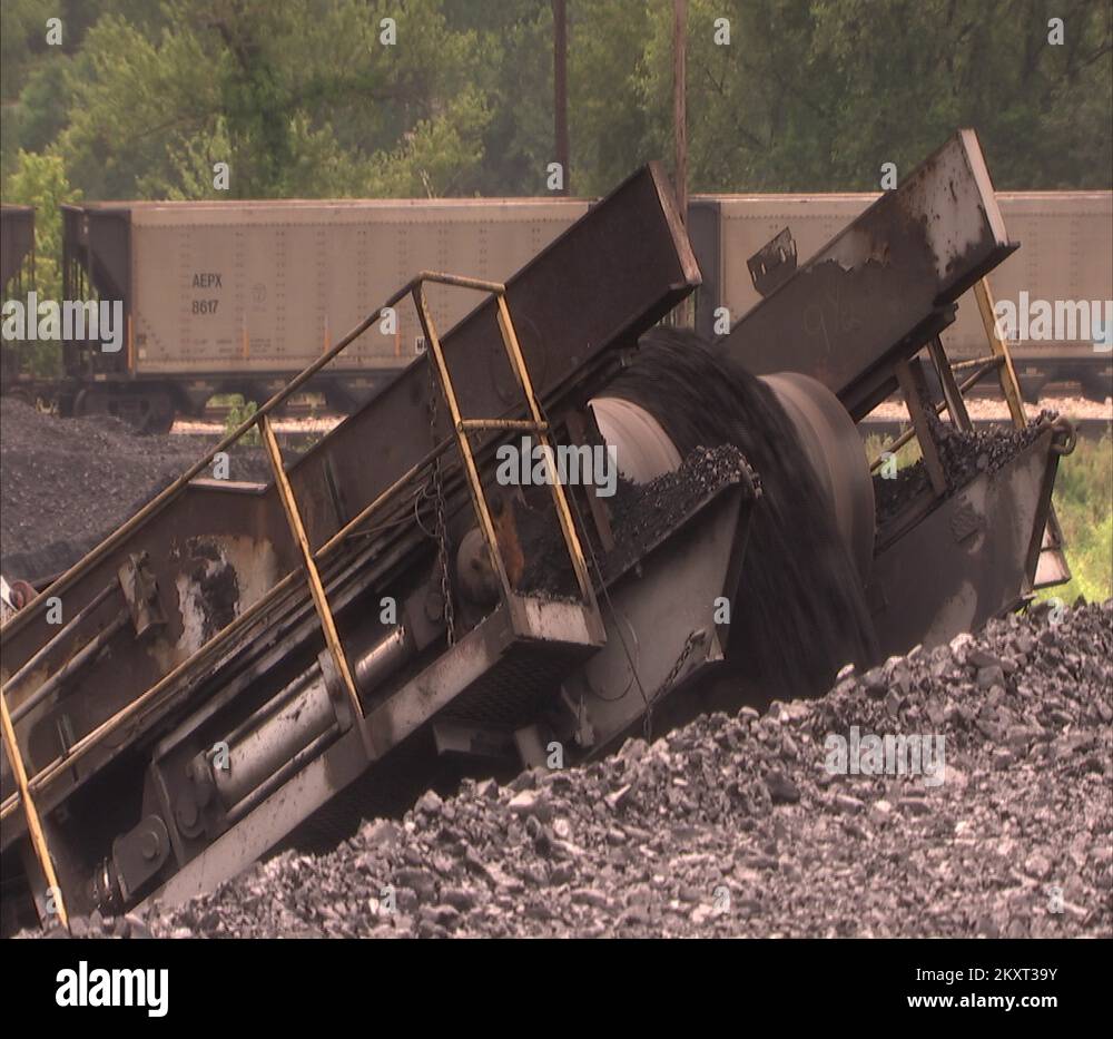 MCU top of moving conveyor with coal; Box car train travels behind ...