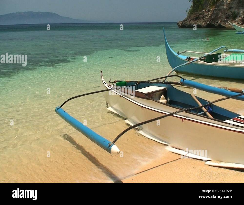Traditional filipino Banka outrigger boat laying on a beach in ...