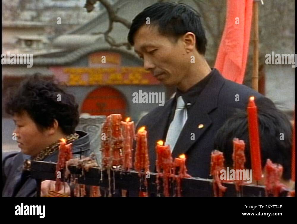 China, Xian, people lighting joss sticks at temple and praying close-up ...