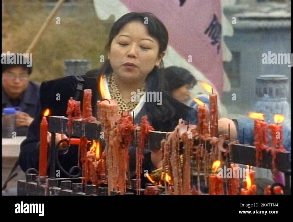 China, Xian, people lighting joss sticks at temple and praying close-up ...