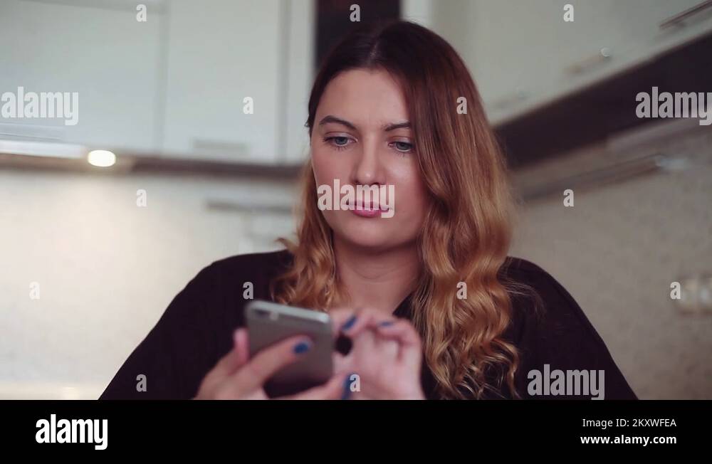 A beautiful young girl dials a phone number on her smartphone and ...