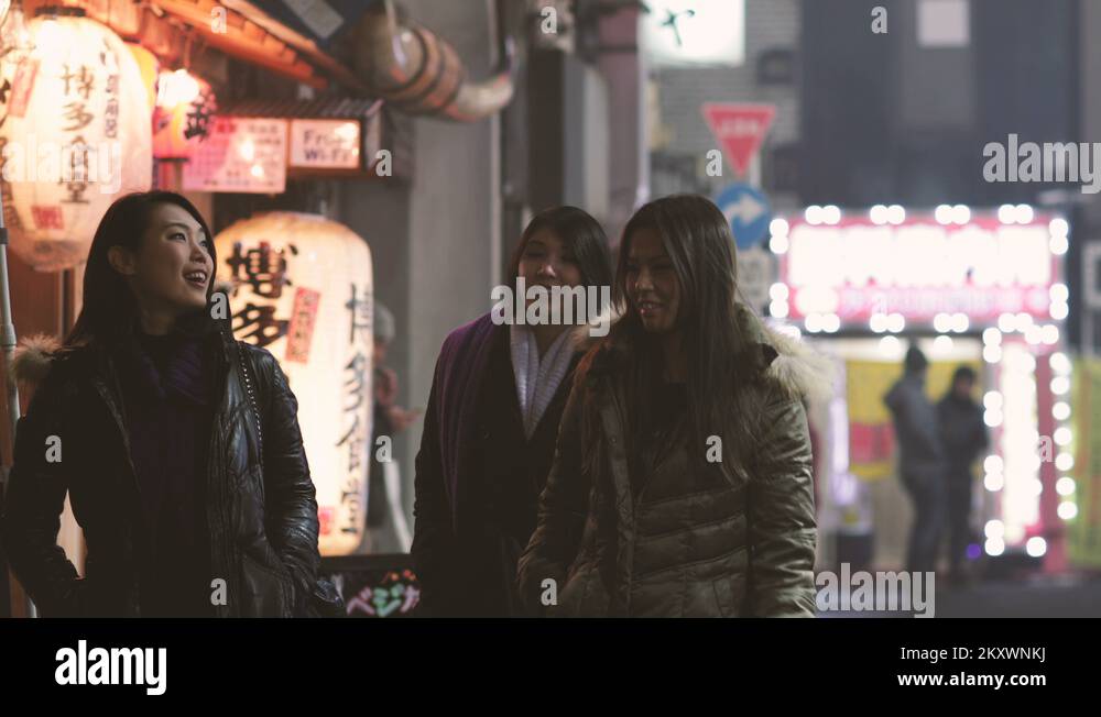 Japanese female friends walking on street in Shinjuku at night, Tokyo ...