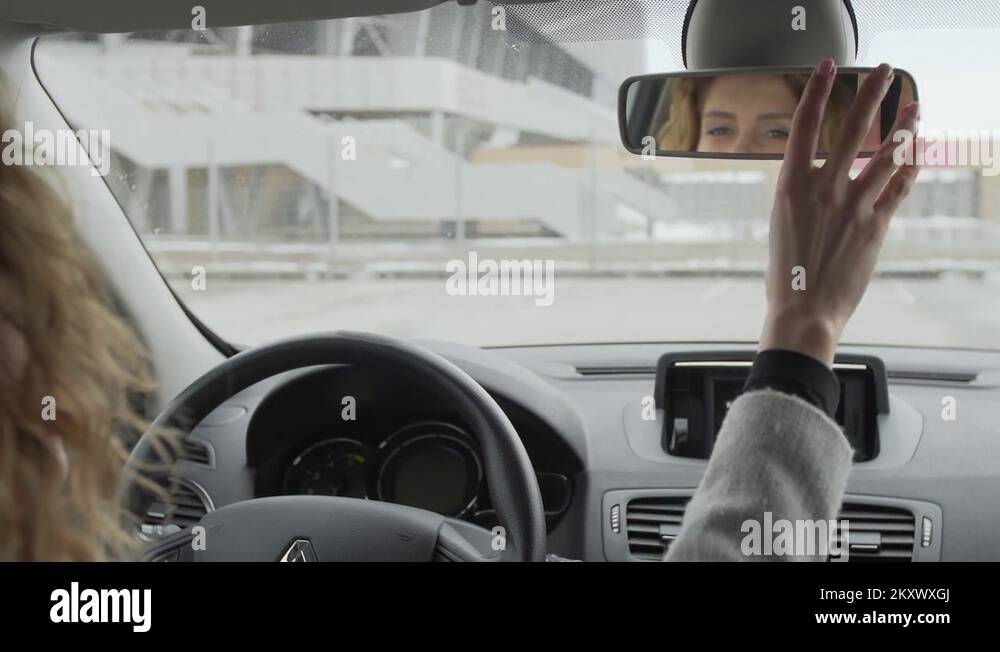 Woman looking at camera through rear view mirror, woman driving car ...