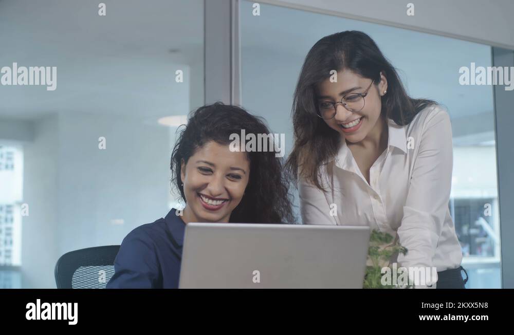 Two attractive Indian female coworkers are smiling while working Stock ...
