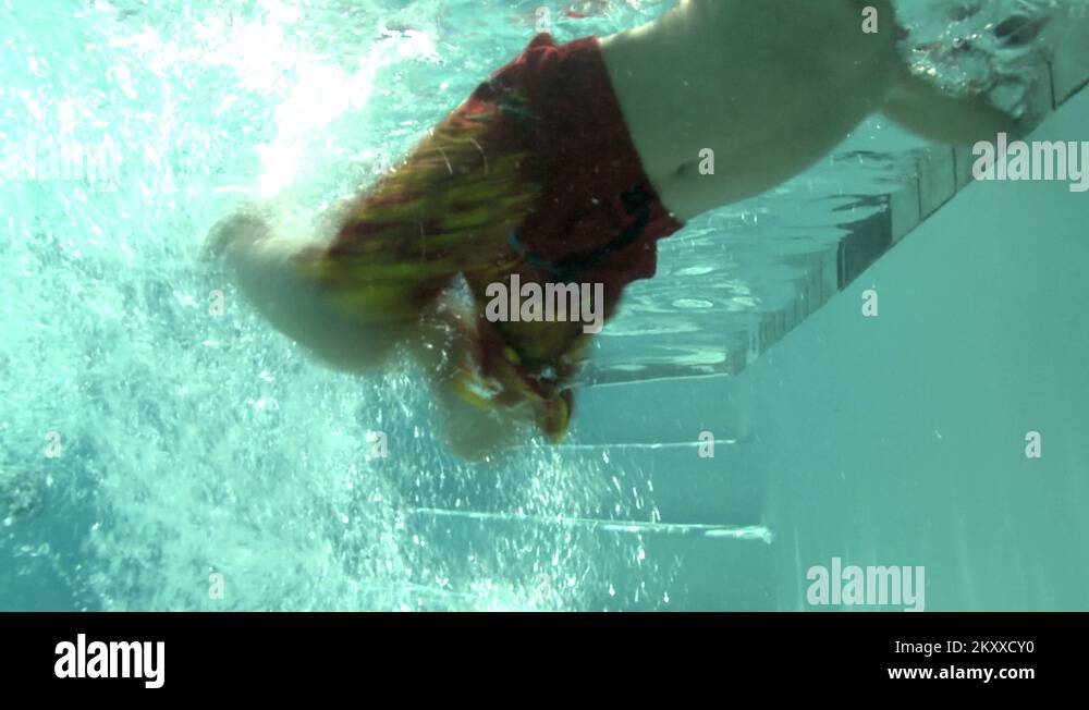 little boy holding onto the side of a swimming pool while kicking Stock ...
