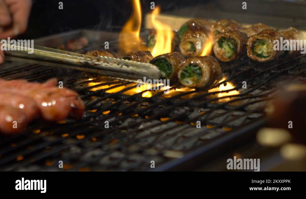 Slow Motion Vendor cooking bacon spring onion wrap steel grill, night ...