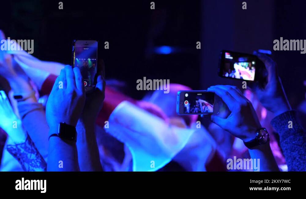 Smart phones in hands spectators crowd dance jump and shoot video of ...