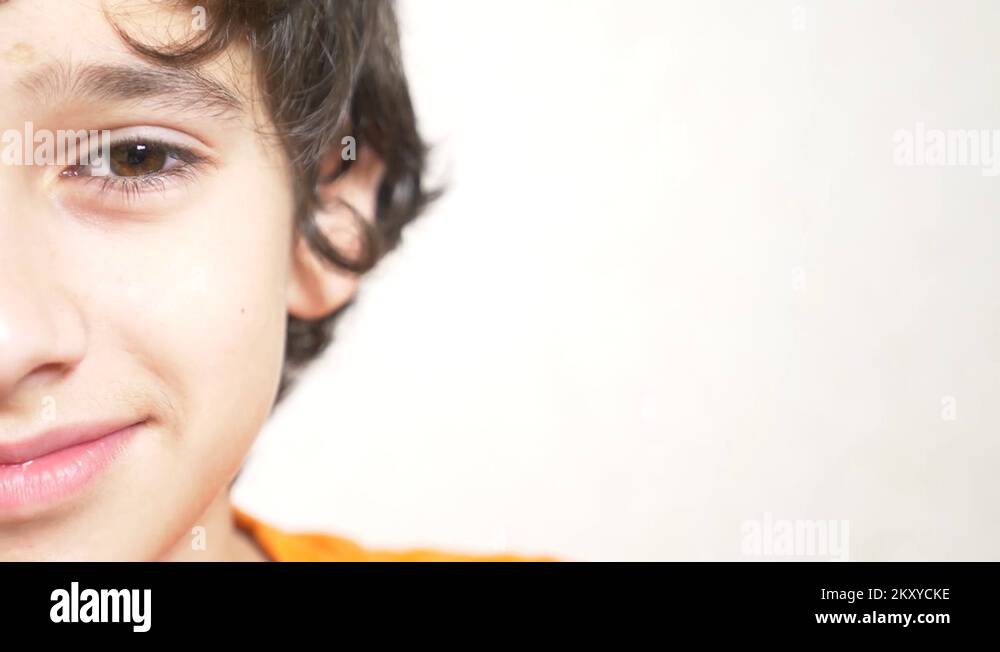 A young boy looks at the camera and smiling. 4k. close-up, half face ...