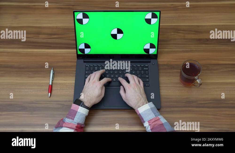 Office table with laptop computer with green screen and male hands ...
