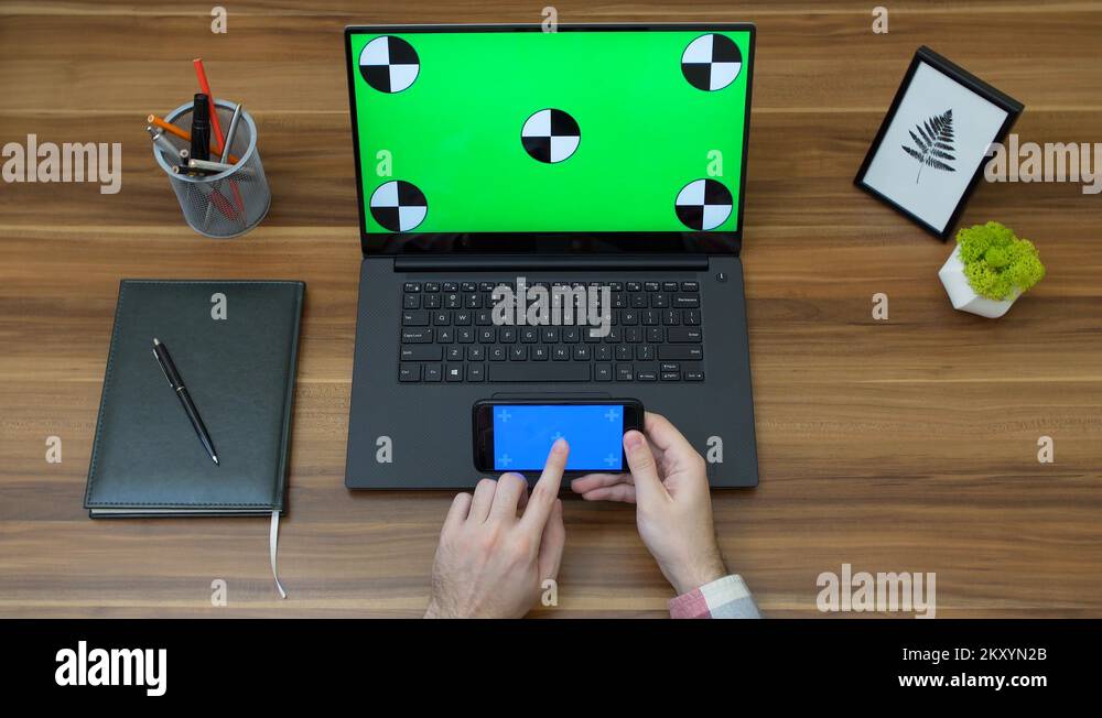 Man's scrolling on the smartphone with blue and a laptop with green ...