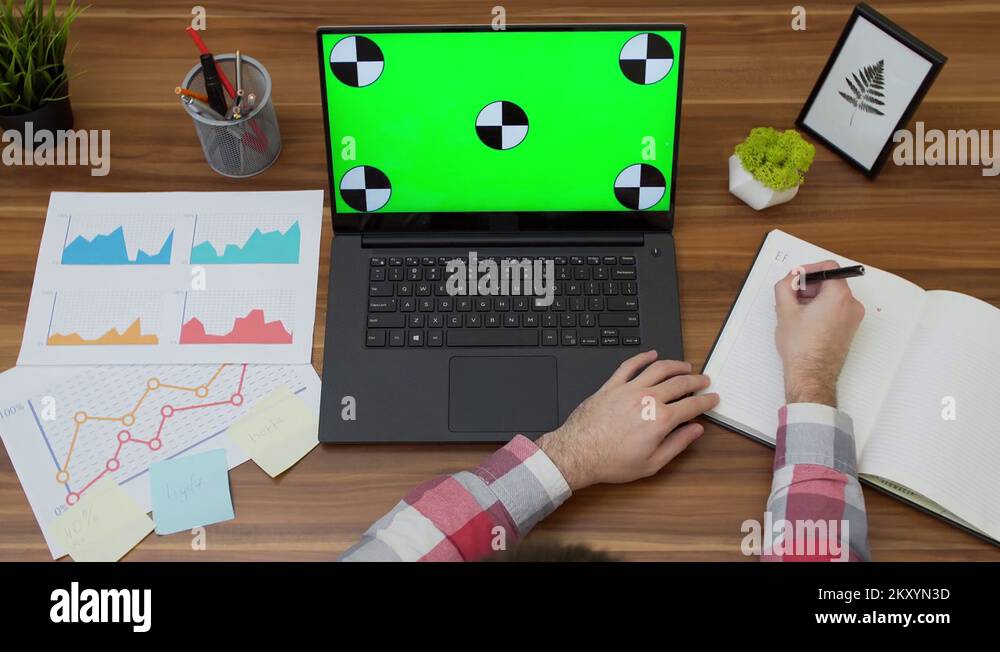 Office table with laptop computer with green screen and male hands ...