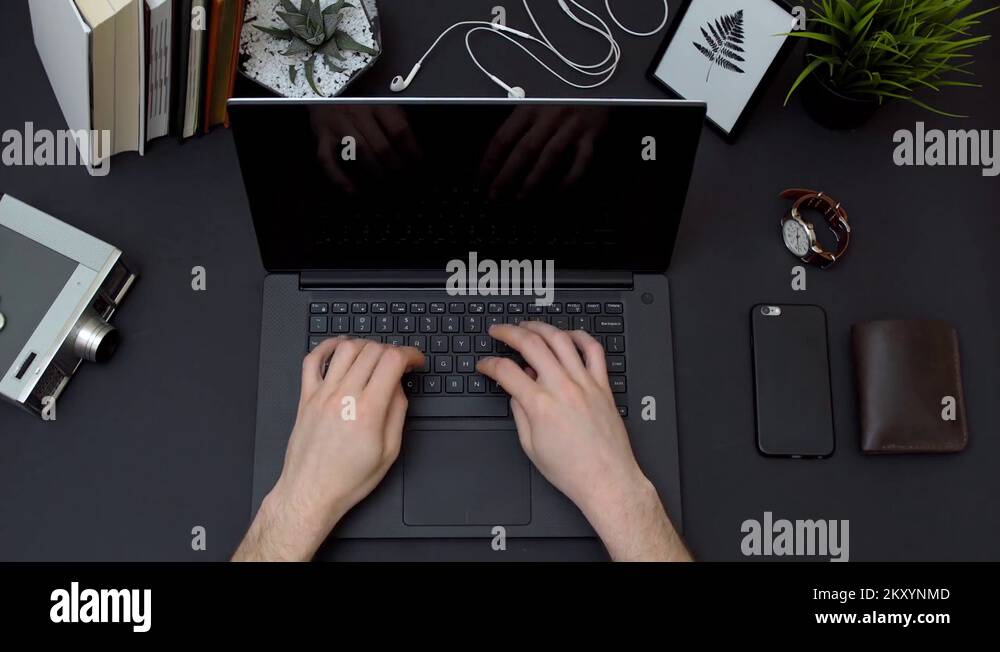 Office table with laptop computer with black screen and male hands ...