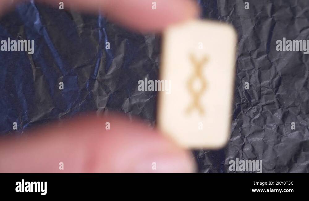 Inguz rune. close-up, hand puts the rune on the surface for divination ...