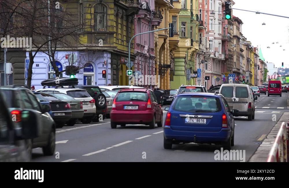 Cars drive down a busy Czech street, then stop at a crosswalk and ...