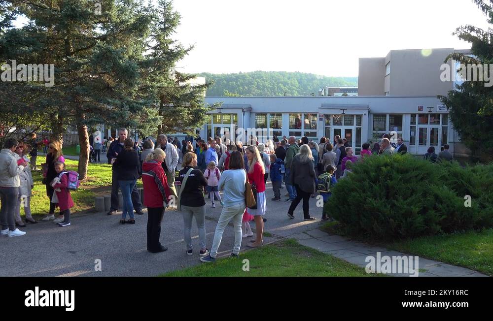 Children and adults stand in front of a school on the first day of ...
