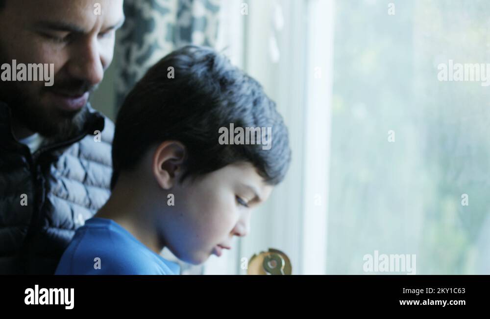 close up of young boy trying to use his father's compass as his dad ...