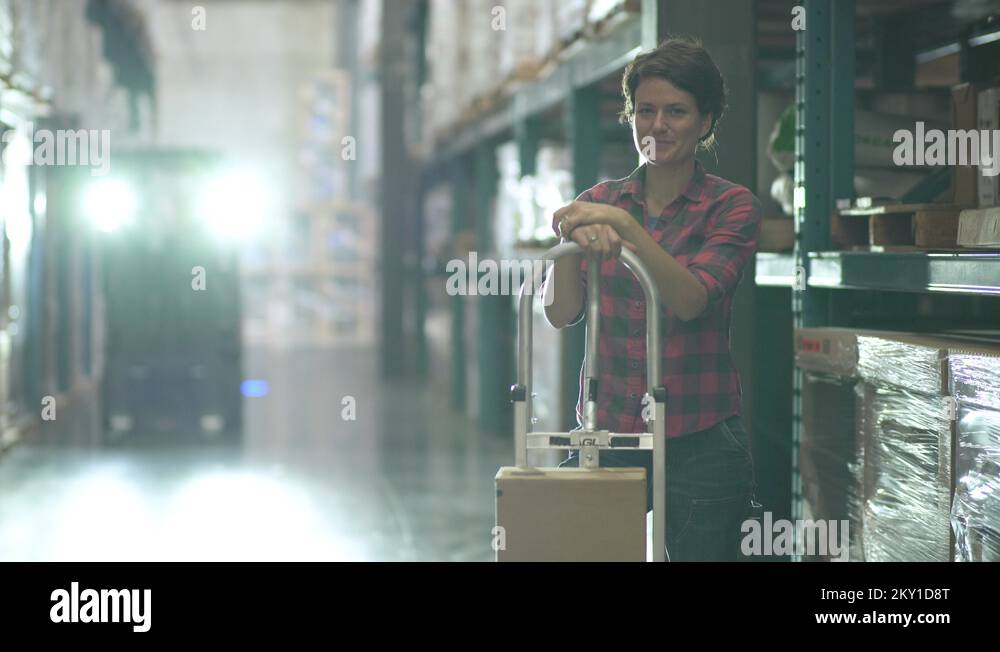 Woman standing and leaning on trolley with stock, looking at camera and ...