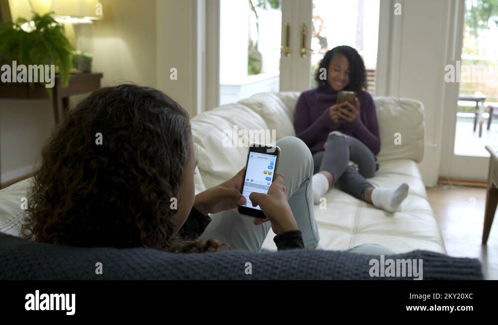Two girls laying on sofa using their mobile phones Stock Video Footage ...