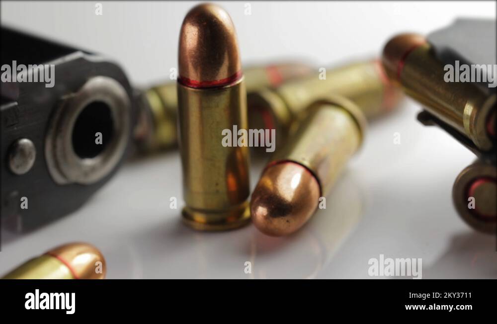 Bullet shells rolling around a hand gun and clip. 9mm caliber ...