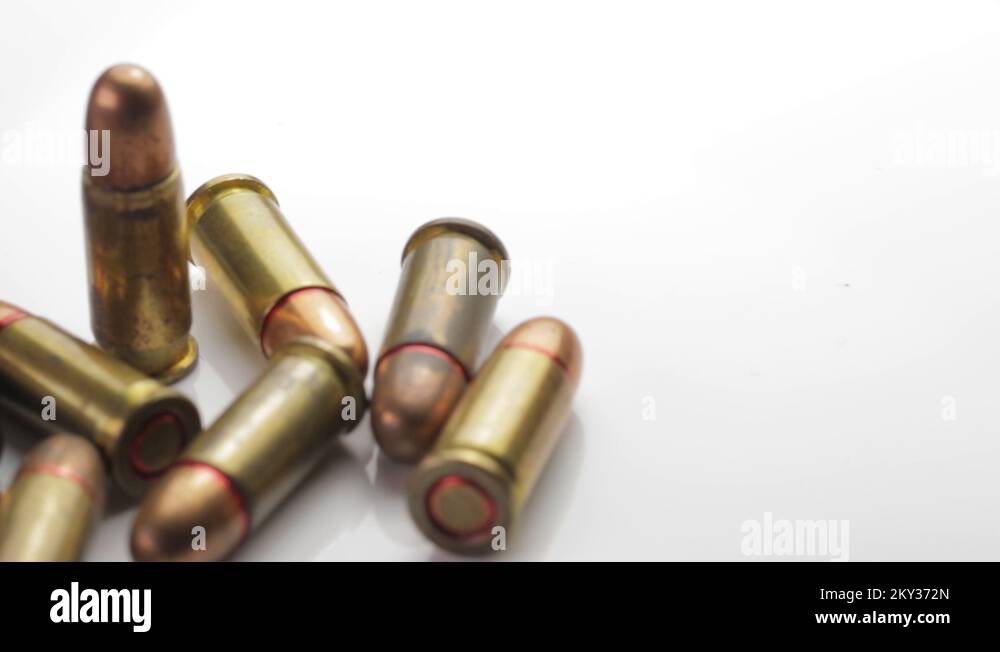 Bullet shells rolling around a hand gun and clip. 9mm caliber ...