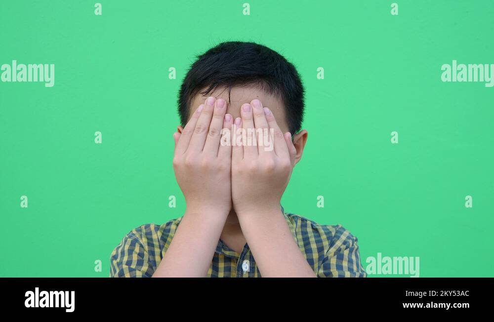 Young boy playing hide and seek in front of green screen Stock Video ...