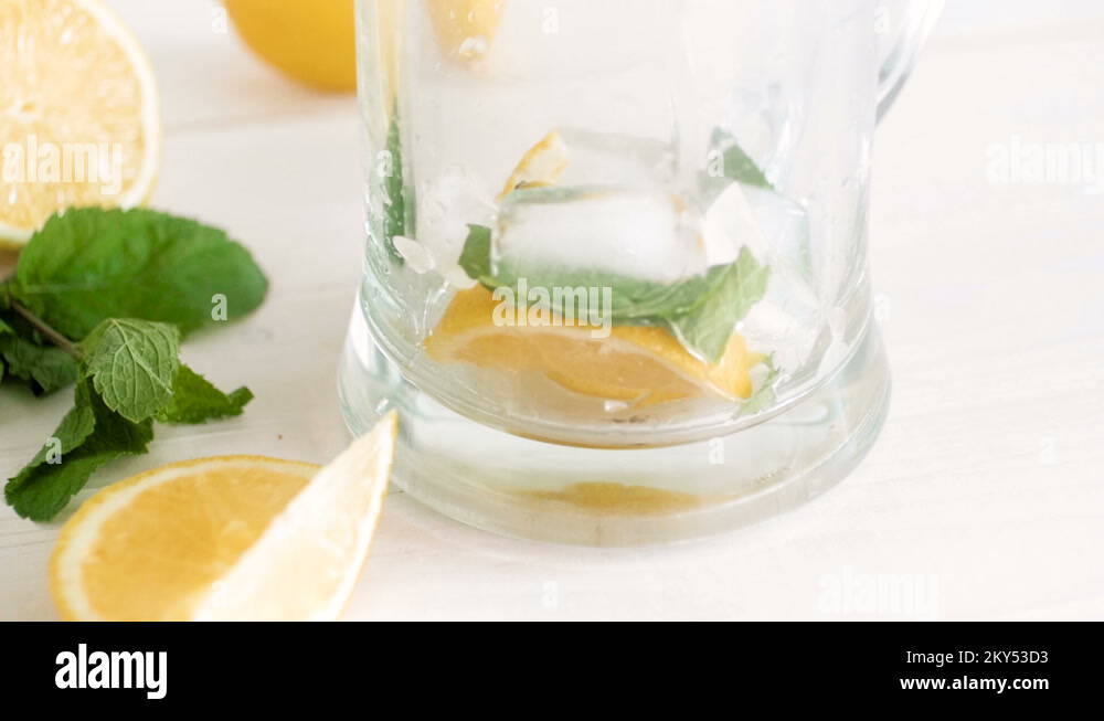 Slow motion footage of pouring carbonated water in glass with ice, lemons and Stock Video ...