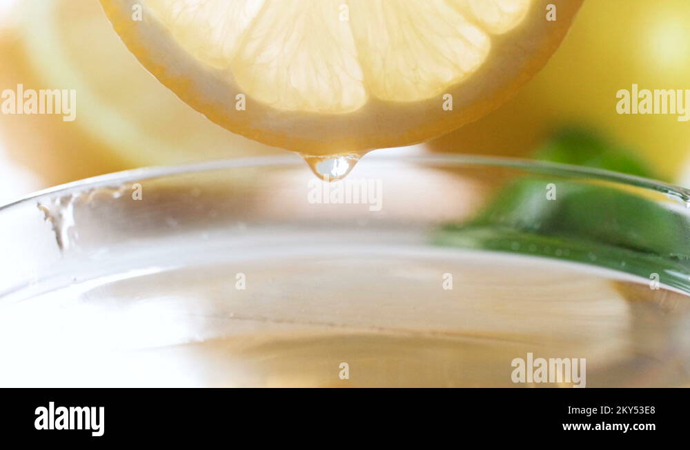 Closeup slow motion footage of juice droplet slowly dripping from lemon ...