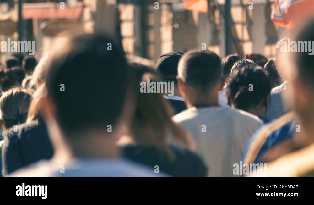 Back view of the crowd of people running on the city street in slow ...