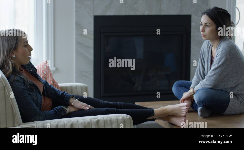 Two young women having intense conversation on couch while husbands ...