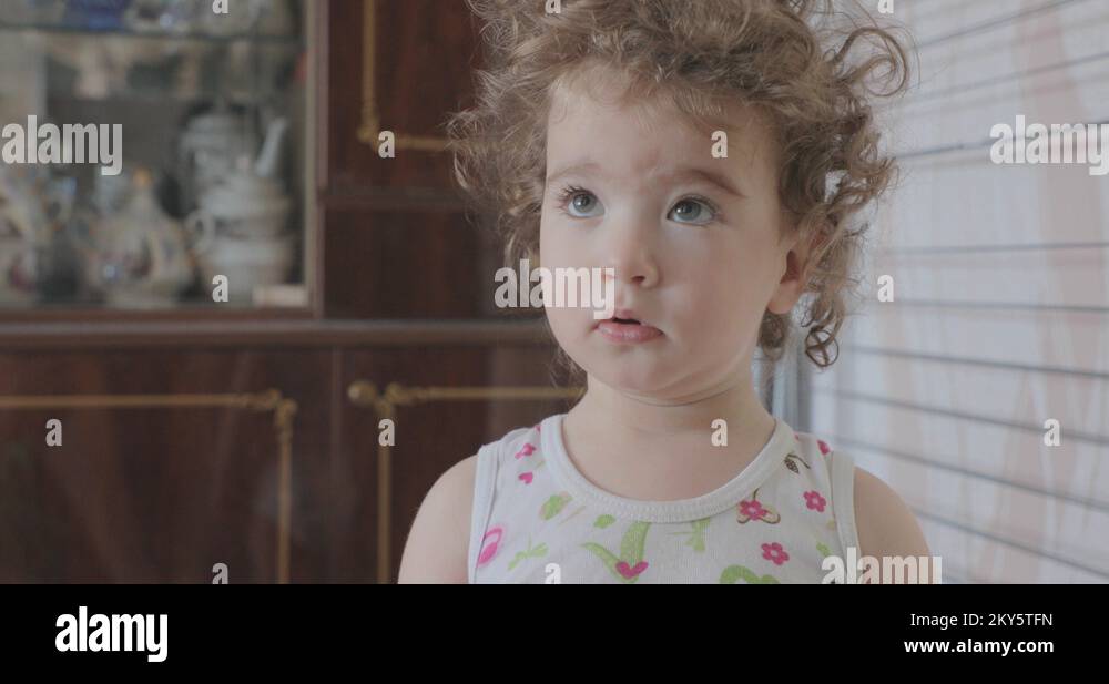 small child with curly hair is looking up and her face is reflecting ...