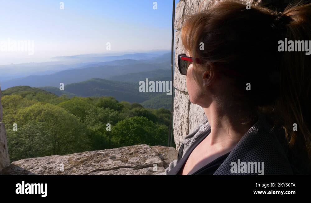 a woman looks at the mountains through a window on the observation ...