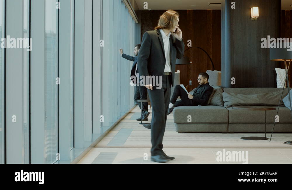 Three men in black suits in front of a panoramic window of modern ...