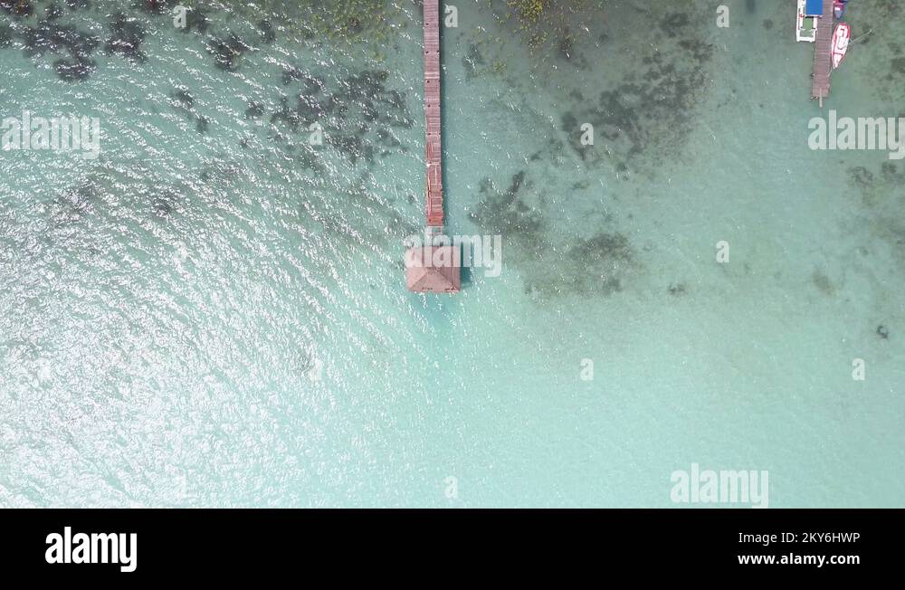 Clear Blue Water Bird's Eye View Drone of Wooden Palm Tree Dock and Hut ...
