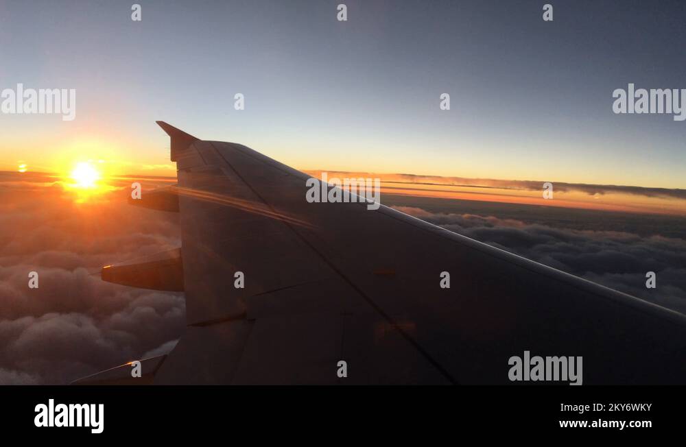 Glorious sun flares over a wing of commercial airliner plane at dusk ...