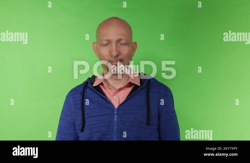 Bald headed Latino man putting baseball hat on in front of green screen ...