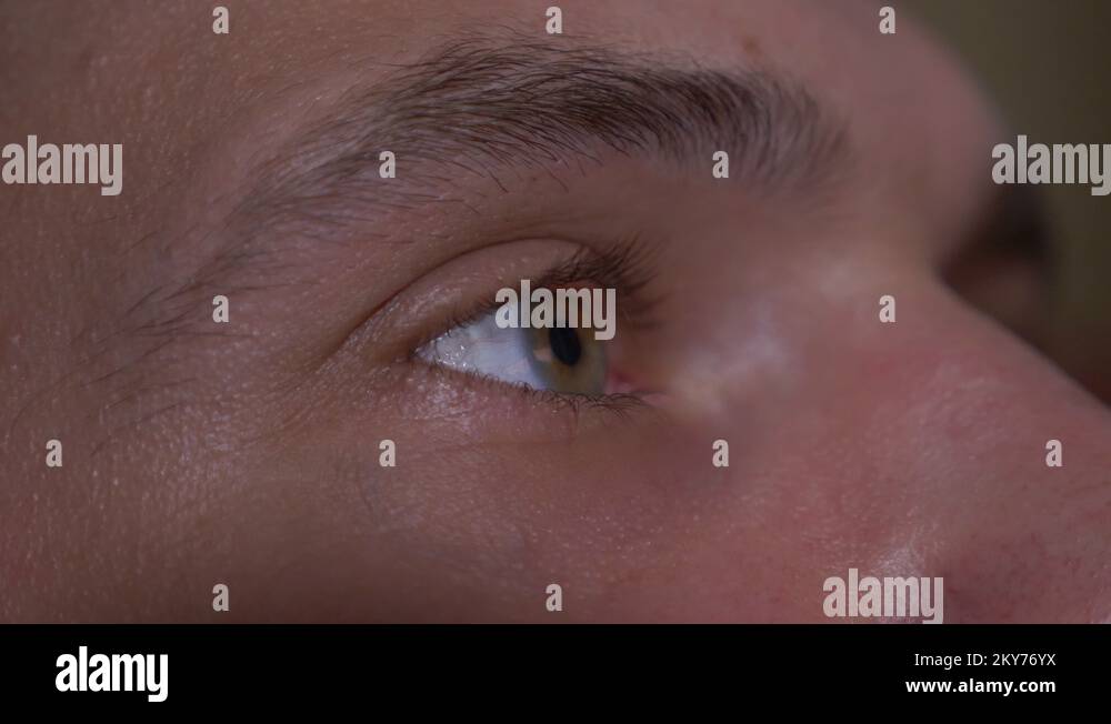 Close-up of a man's human eye. the man looks closely at the TV screen ...