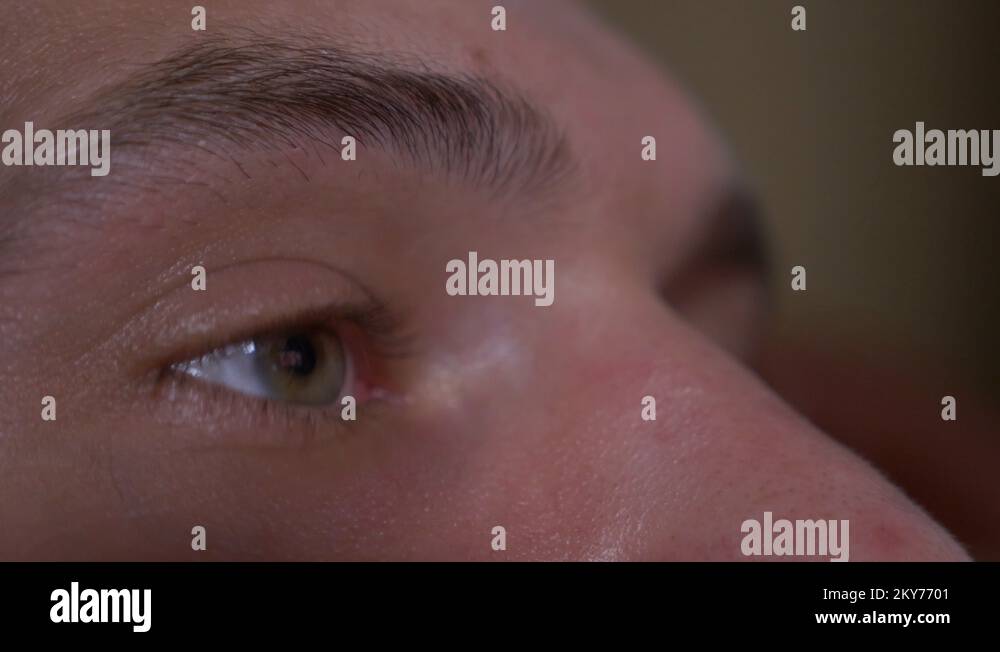 Close-up of a man's human eye. the man looks closely at the TV screen ...