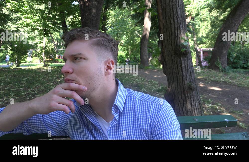 Overwhelmed stress moments angry young casual man sitting on bench park ...
