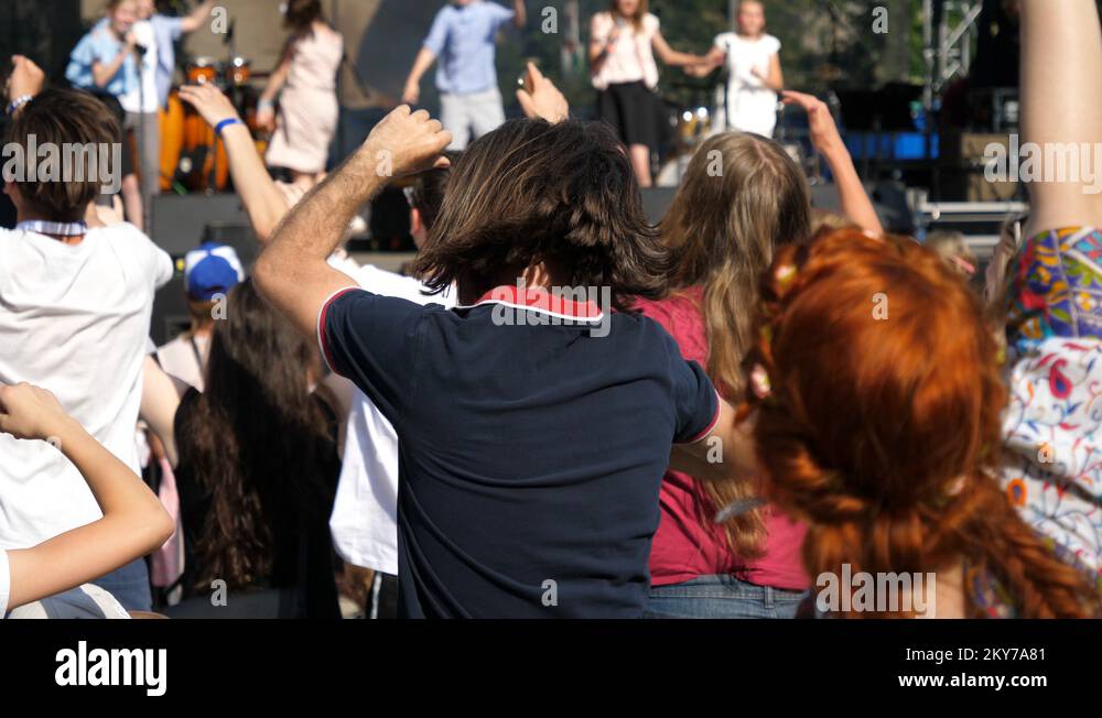 Young spectators audience people raise wave hands enjoy free open air ...