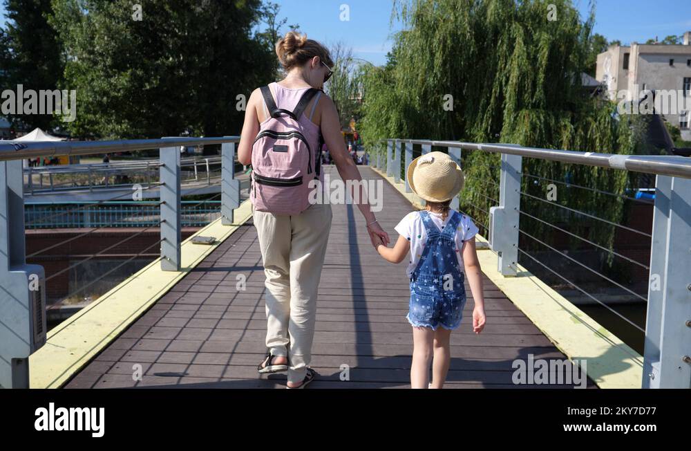 Young mother and child girl daughter walk pedestrian bridge together ...