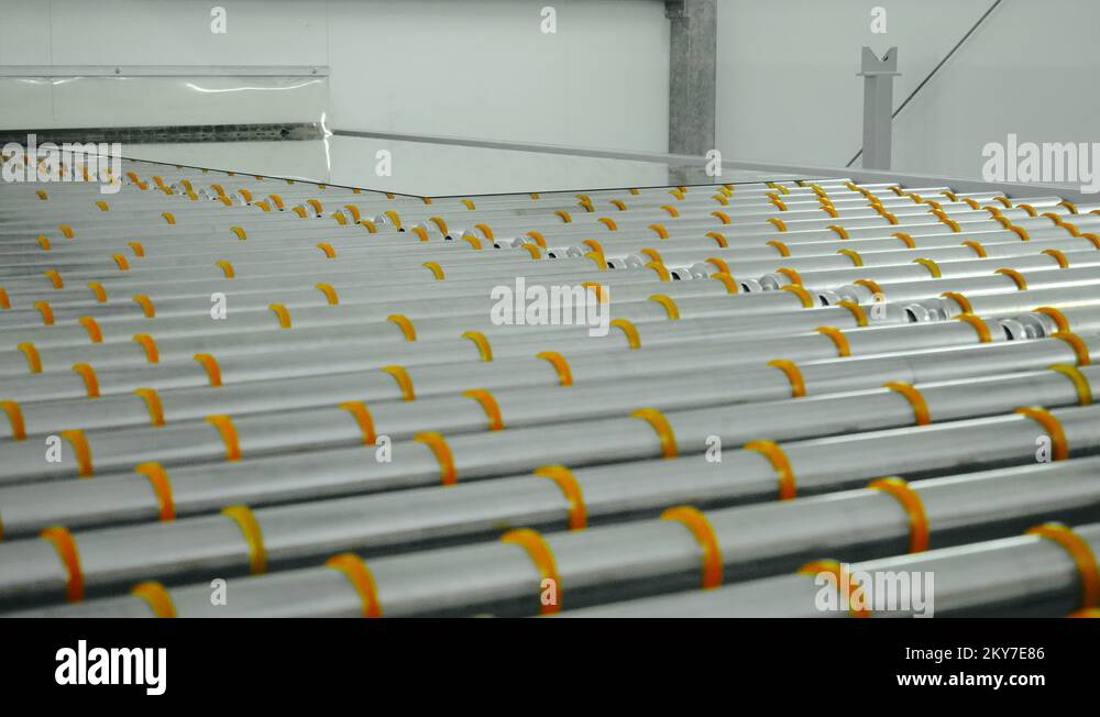 Sheet of transparent glass moving on automated conveyor belt at ...