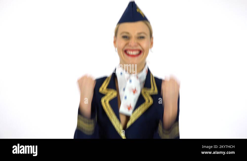 A young beautiful stewardess celebrates and smiles at the camera ...