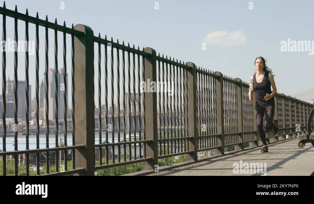 An attractive young woman jogging in New York City, wearing running ...