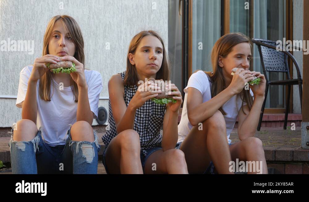 Triple sisters twins teen girls sitting on backyard porch terrace eat ...