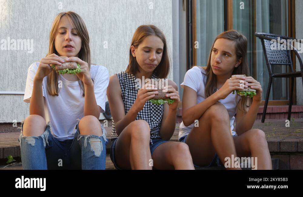 Triple sisters twins teen girls sitting on backyard porch terrace eat ...