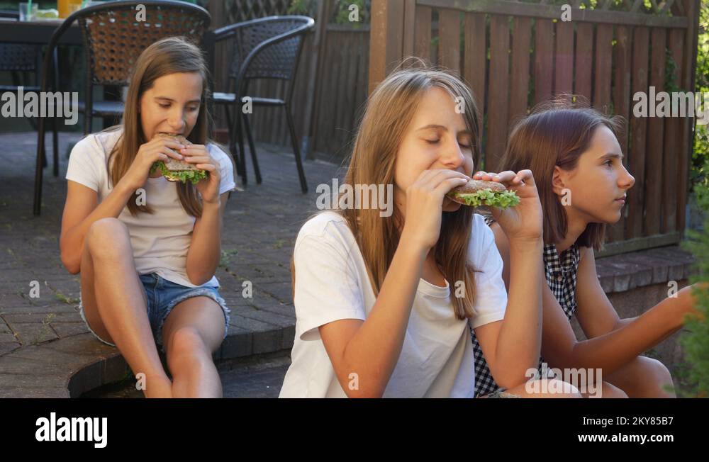 Triple sisters twins teen girls sitting on backyard porch terrace eat ...