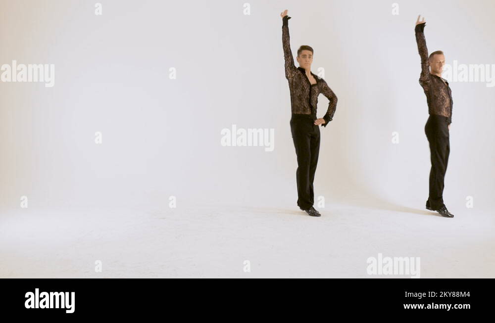 Two men, ballet dancers, dancing in the studio on a white background ...