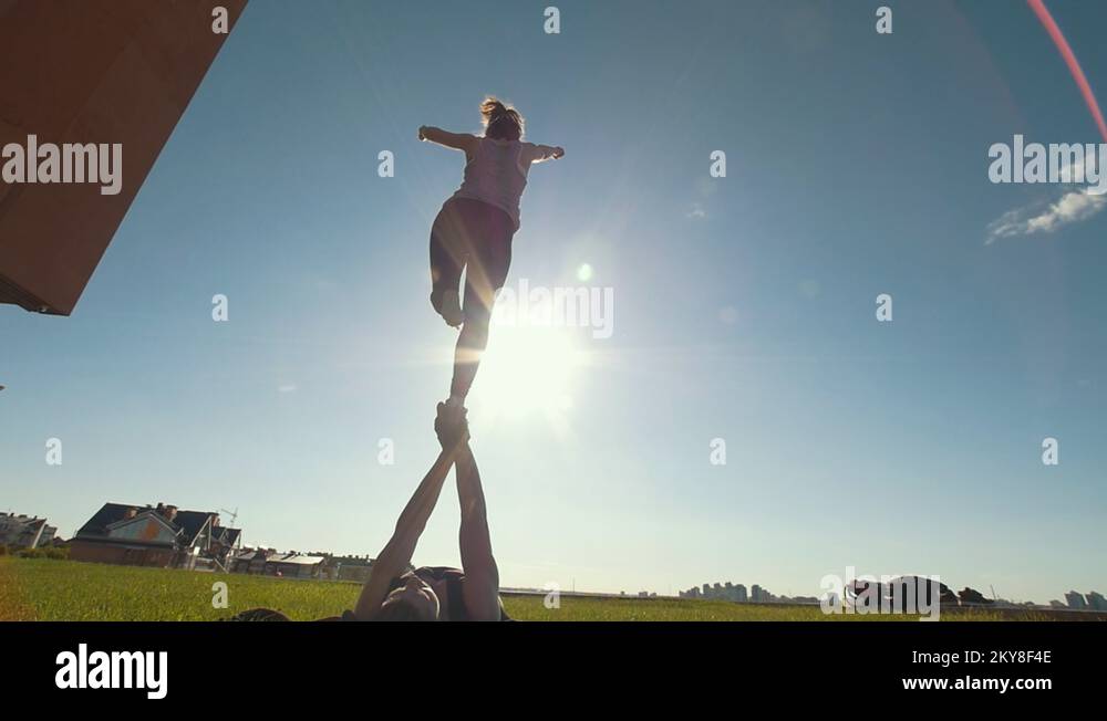 Couple performing front plank bird pose, young man holding flying girl ...
